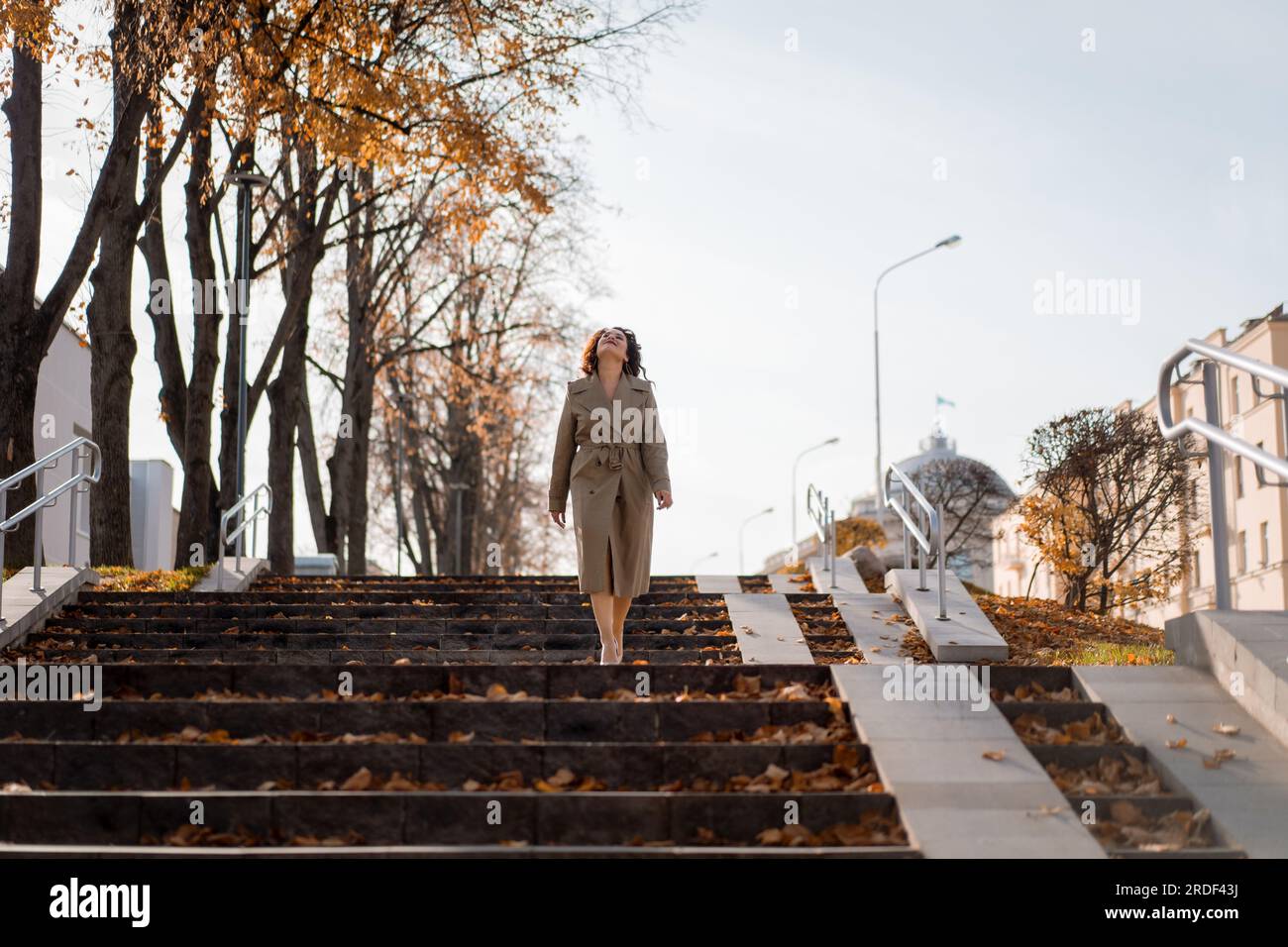 Young woman walking down the steps on street through the autumn city ...