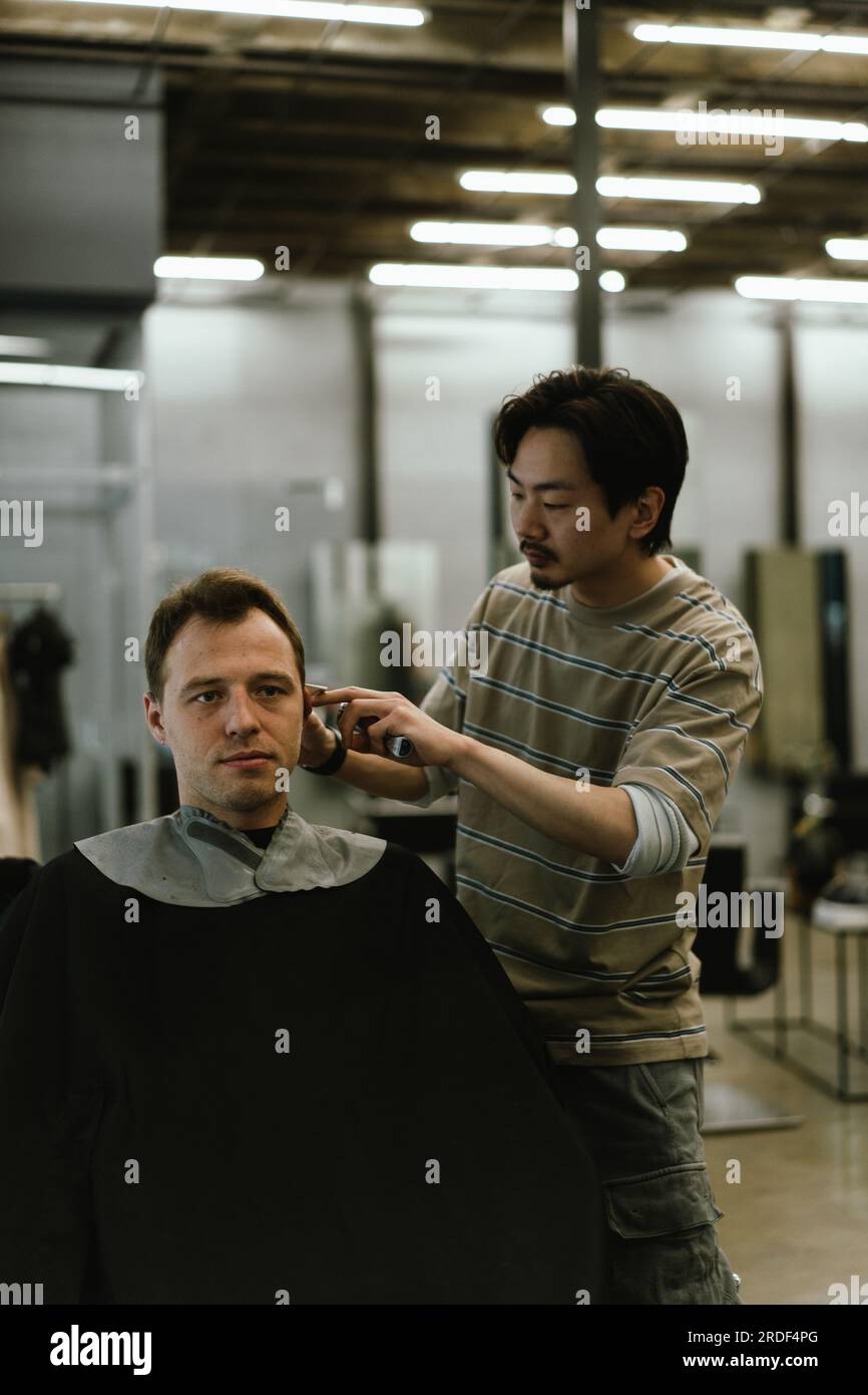 A Japanese barber cuts the hair of a man client at a barbershop Stock ...