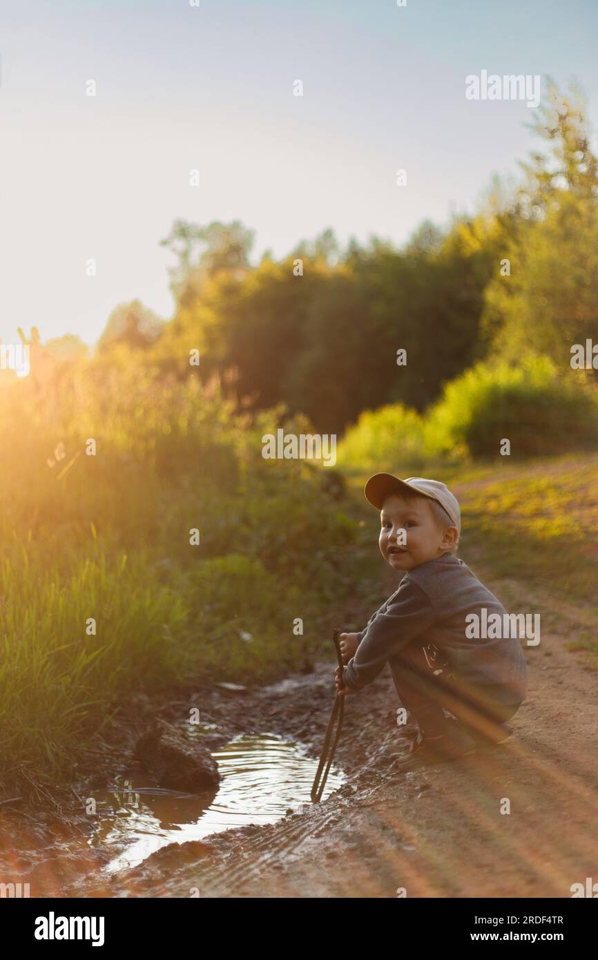Boy playing in puddle with sticks Stock Photo - Alamy