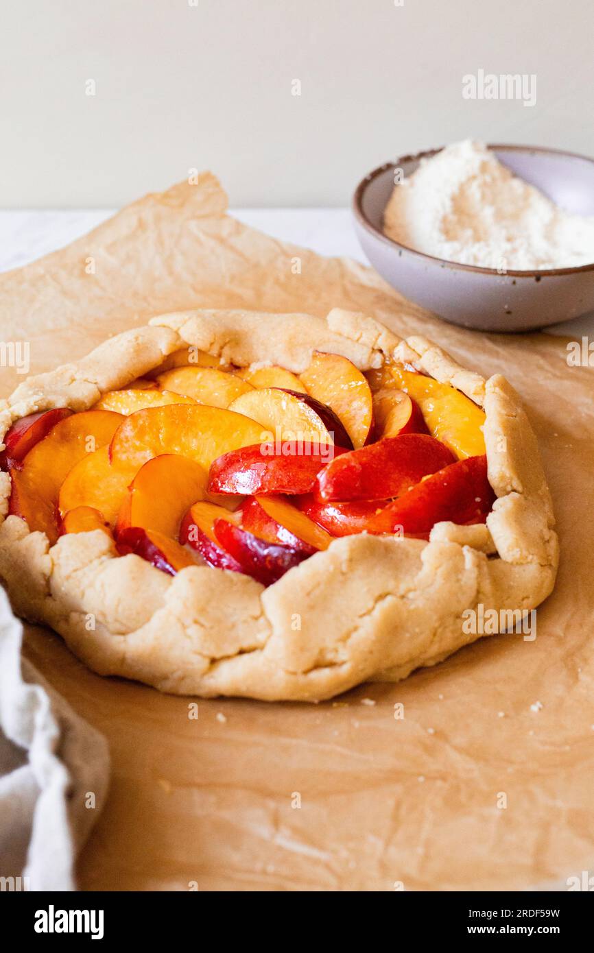A nectarine galette sitting on parchment paper before baking Stock ...