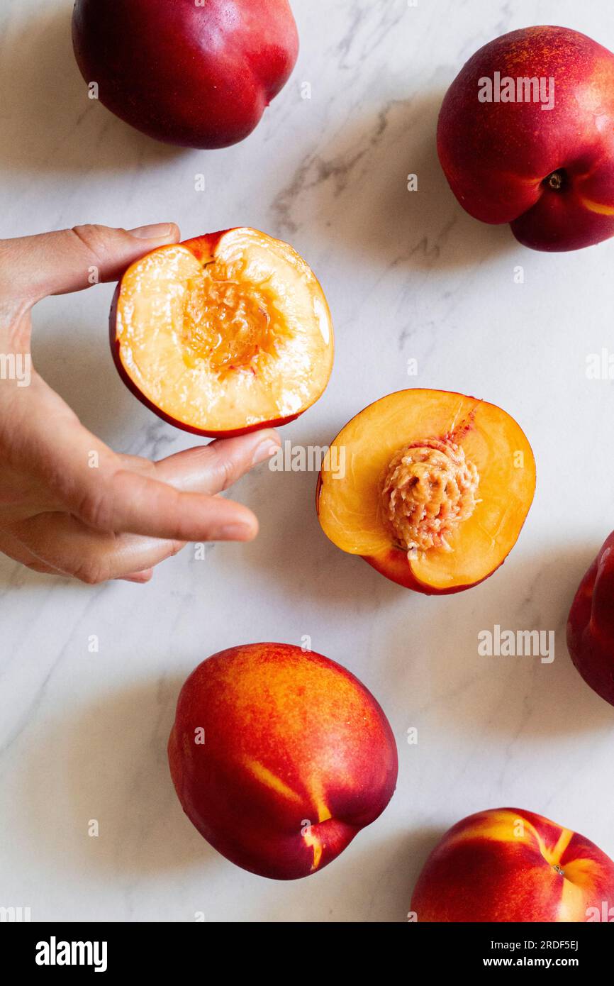 Hand grabbing a ripe, juicy, nectarine that is cut in half Stock Photo ...