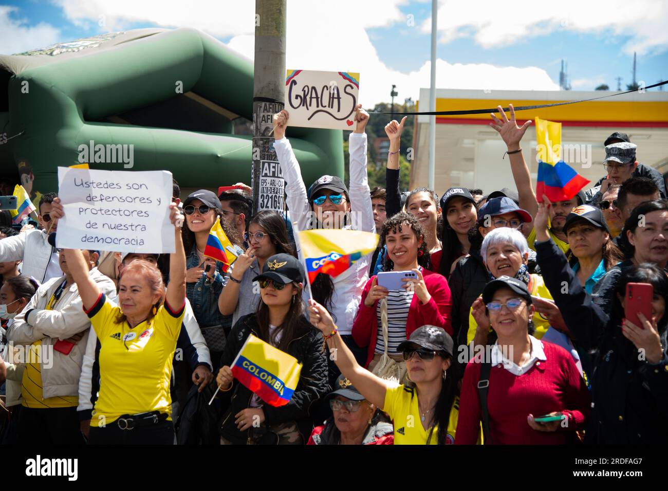Parade viewers hold signs in support of the military and wave Colombian ...
