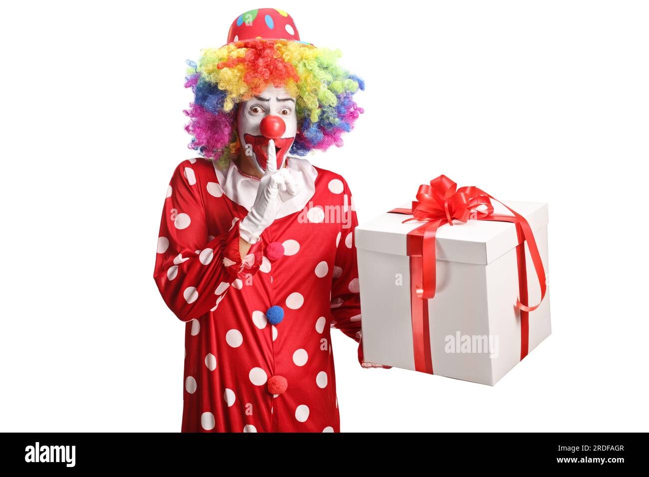 Clown with a birthday present making a finger mouth shush sign isolated ...