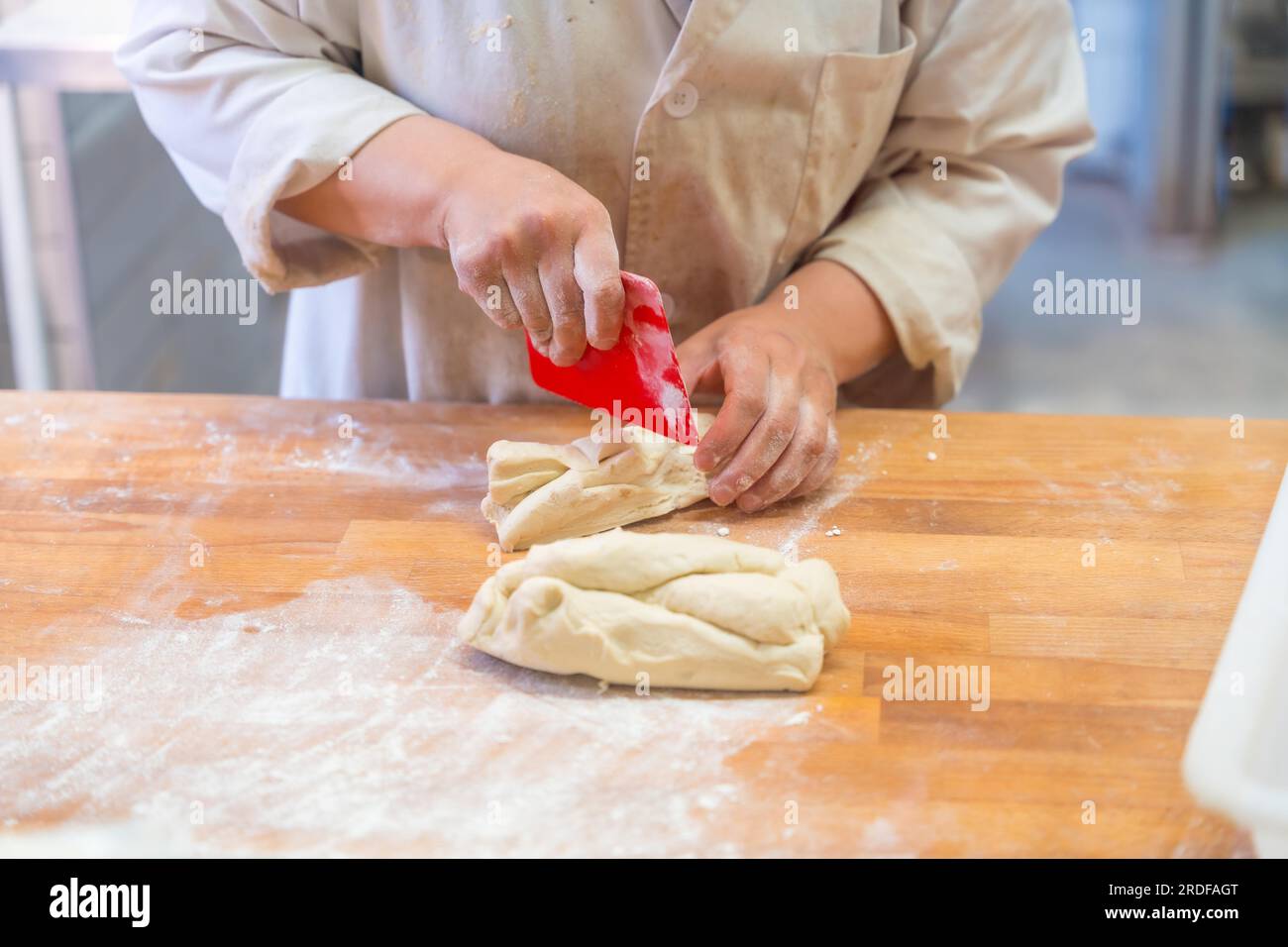 Woman breadmaker employee in the workshop of artisan bakery cutting ...