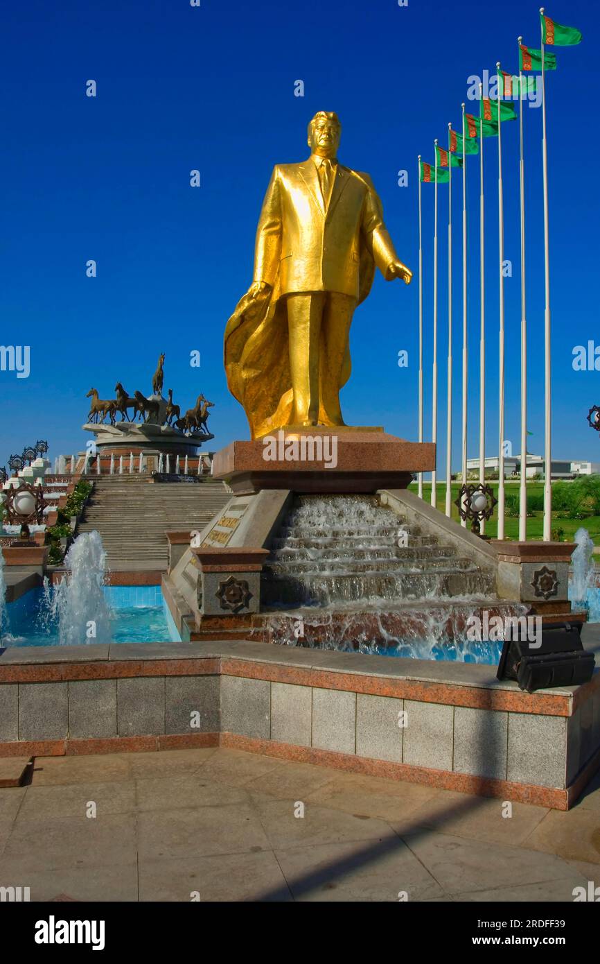 Gilded statue of President Turkmenbashi, in front of monument of the ...