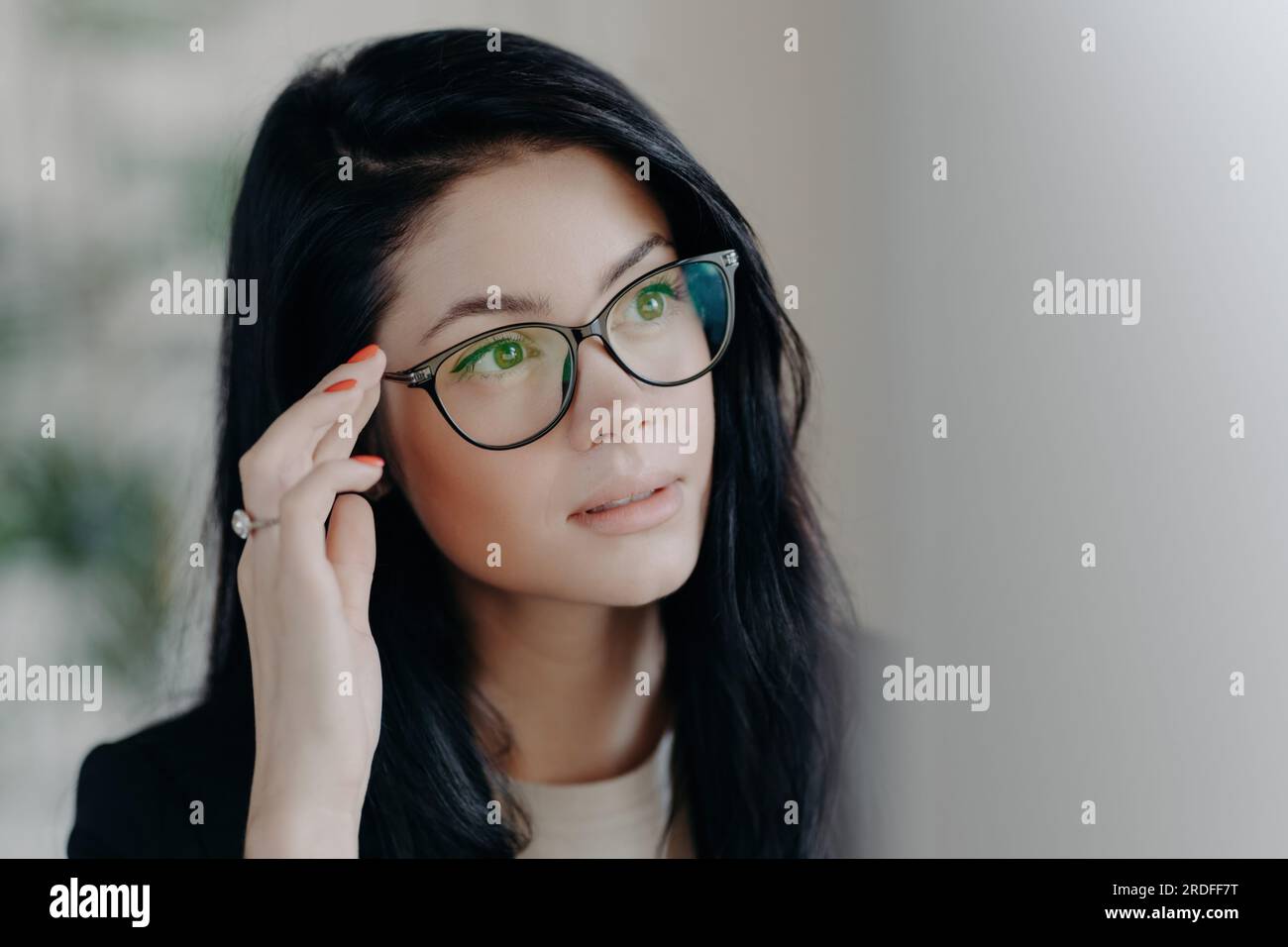 Serious brunette with spectacles, focused on screen, browsing web ...