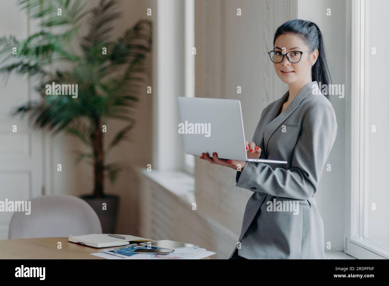 Formal administrative woman with modern laptop, using wireless internet ...