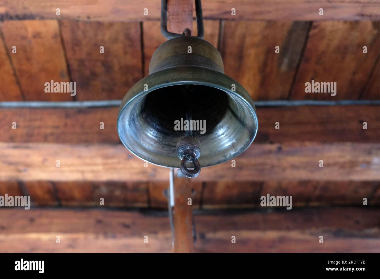 Close-up of a metal bell on a wooden ceiling. Bell in the chapel ...