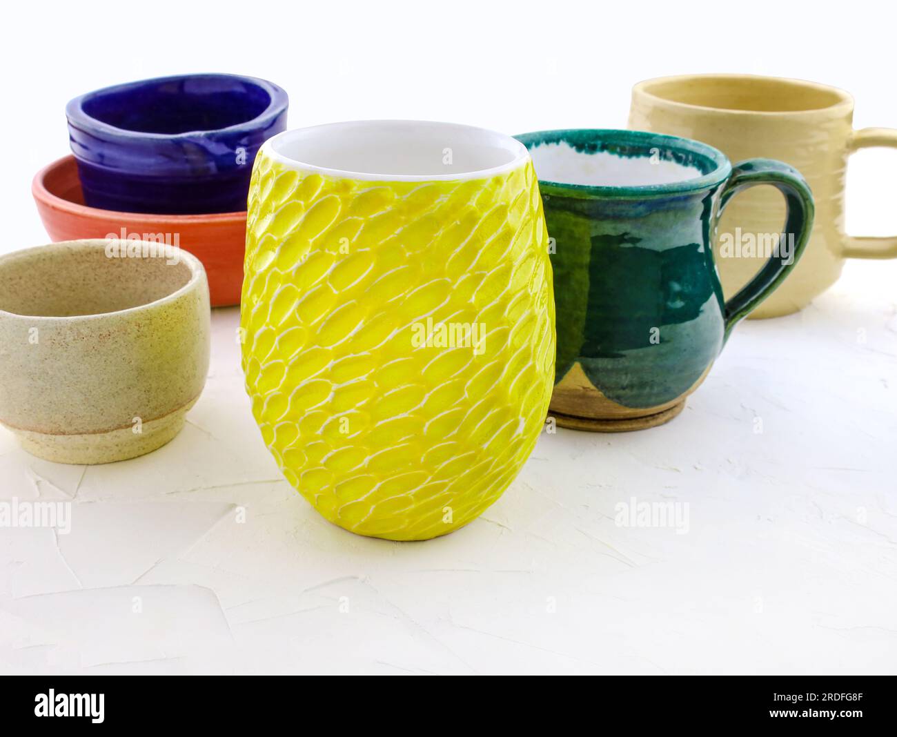 Ceramic cups of different colors and sizes close-up. Multi-colored cups ...