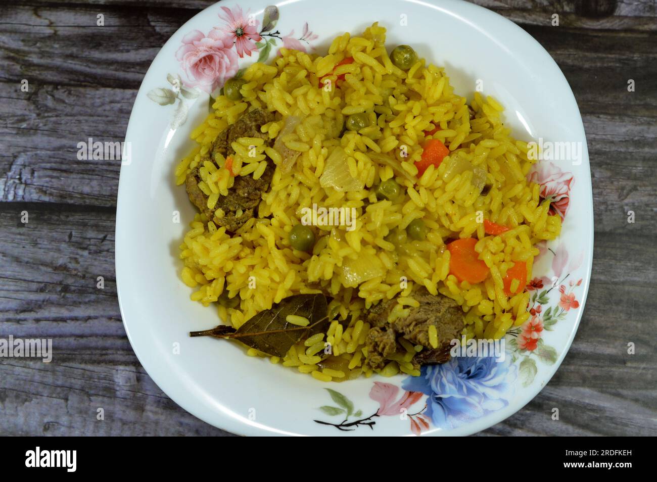 A plate of hot steamed long grain yellow Basmati rice with vegetables ...
