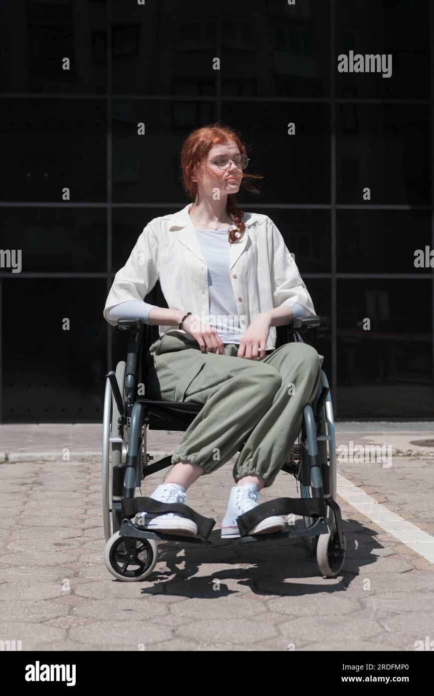 In front of a modern corporate building, a young woman sitting in a ...