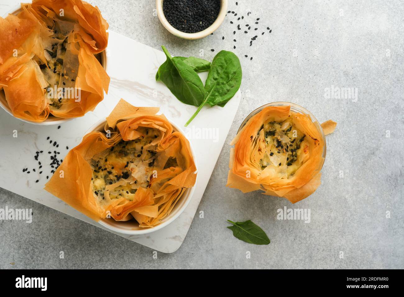 Filo pies with soft feta cheese and spinach in ceramic molds on old ...