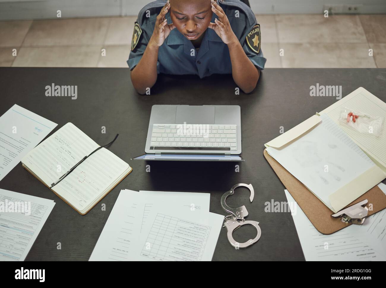 Police, woman and working with stress at desk with documents, paperwork ...
