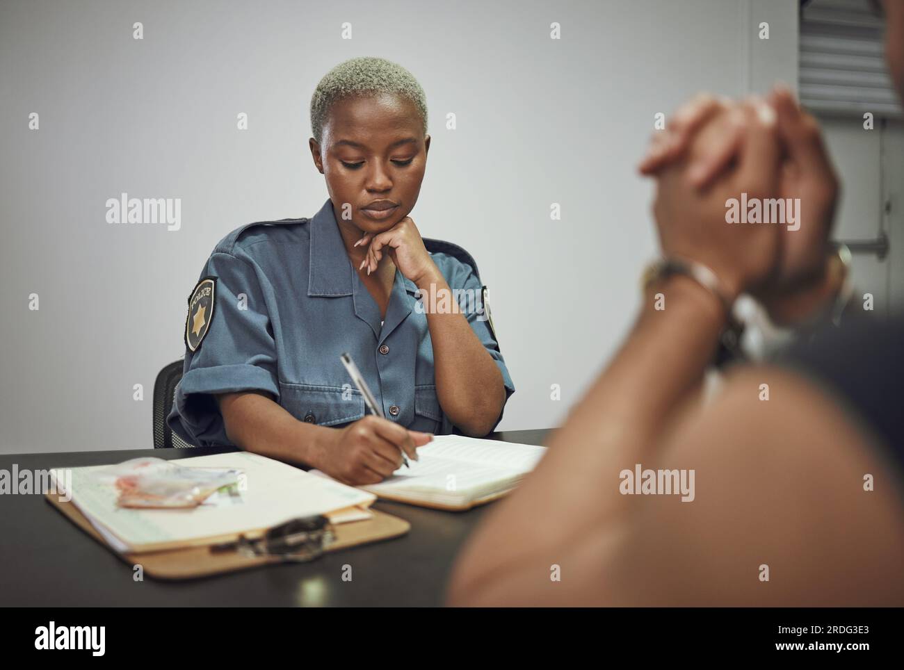 Security, criminal and female police officer at the station writing a ...