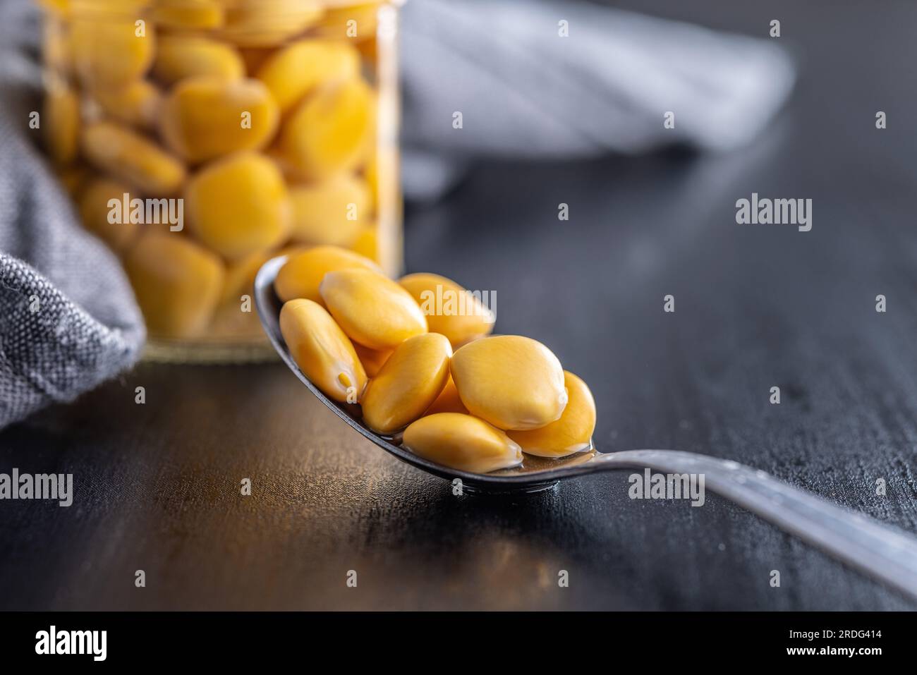 Lupini beans in brine. Pickled lupin in spoon on the black table Stock ...