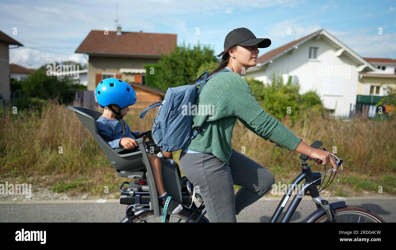 Cyclist mother rides bike outside in green road with child Stock Photo ...