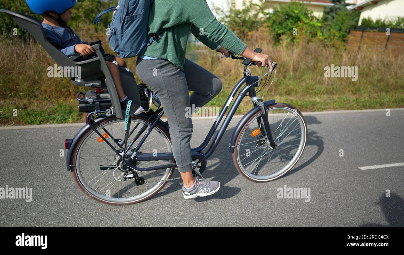 Cyclist mother rides bike outside in green road with child Stock Photo ...