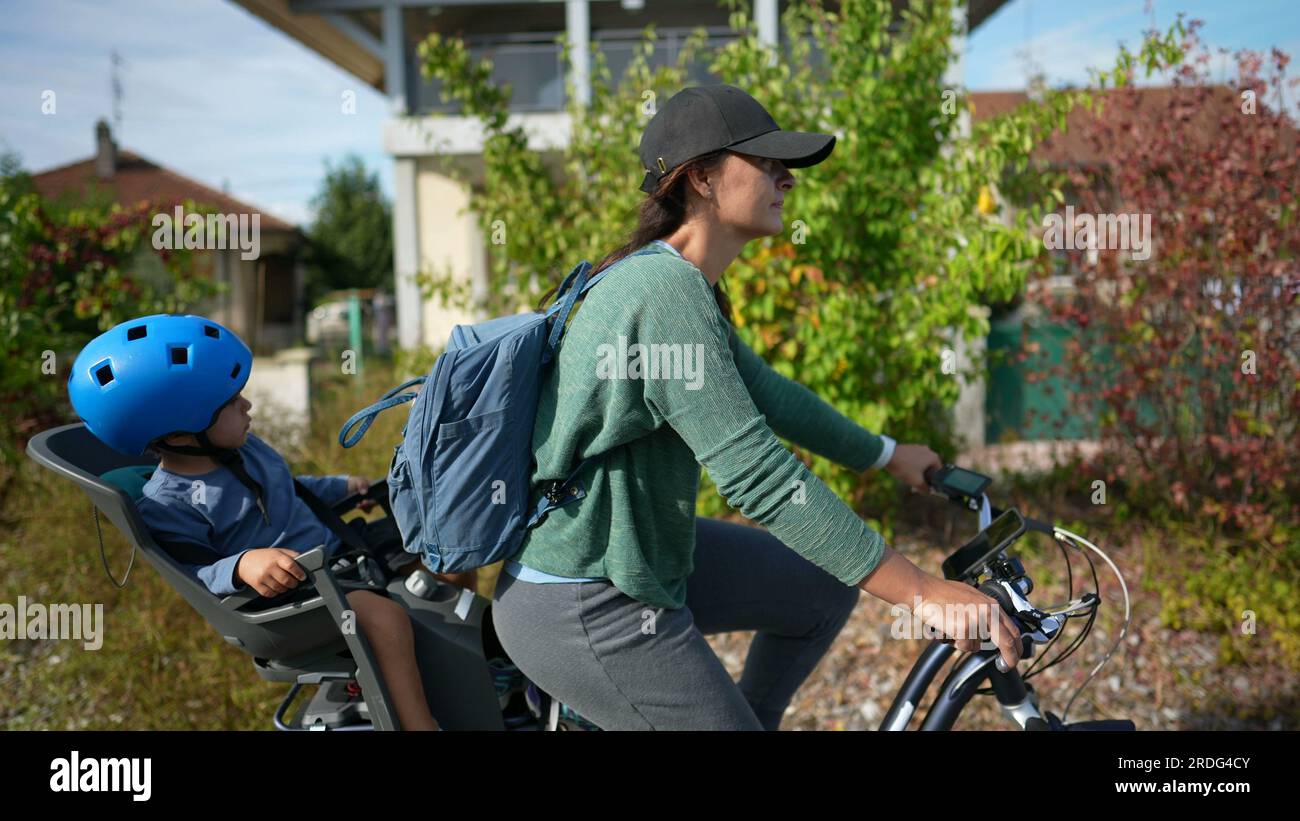 Cyclist mother rides bike outside in green road with child Stock Photo ...