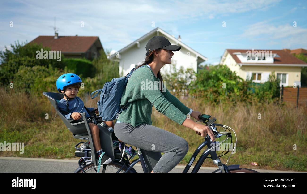 Cyclist mother rides bike outside in green road with child Stock Photo ...