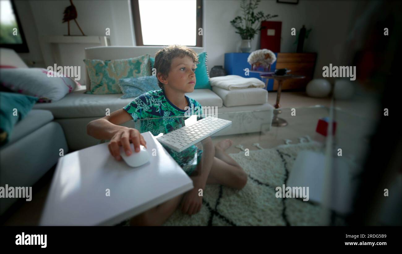 Little boy looking at computer screen in the morning browsing internet ...
