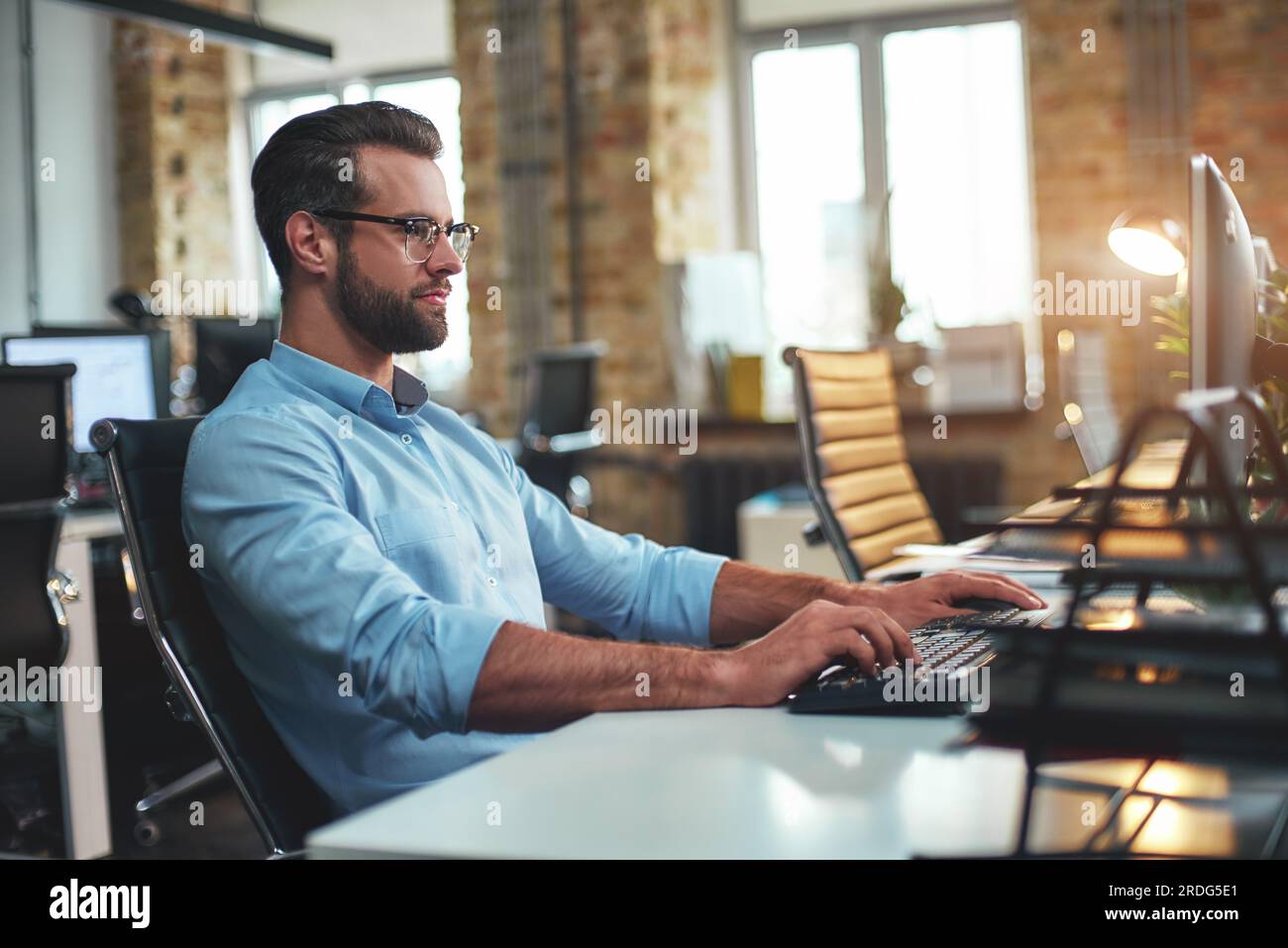 Full concentration. Side view of young bearded man in eyeglasses and ...