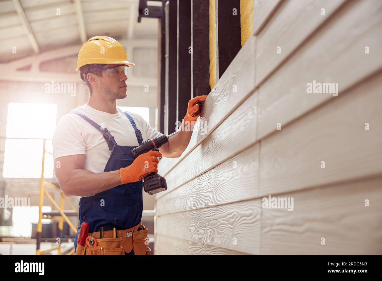 Handsome young man builder installing exterior wood siding Stock Photo ...