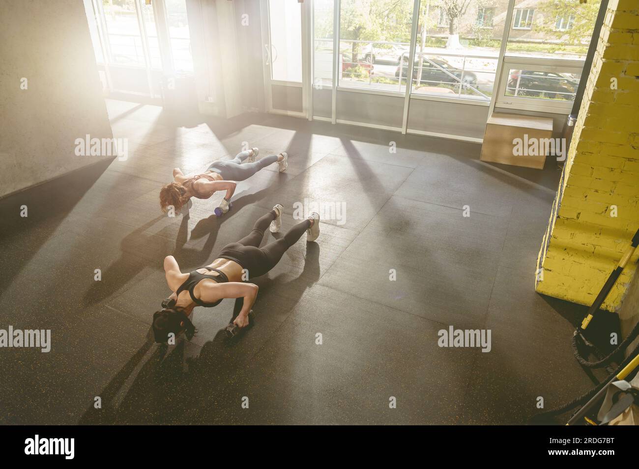 Top view of two sporty women doing push-up exercise with dumbbell ...