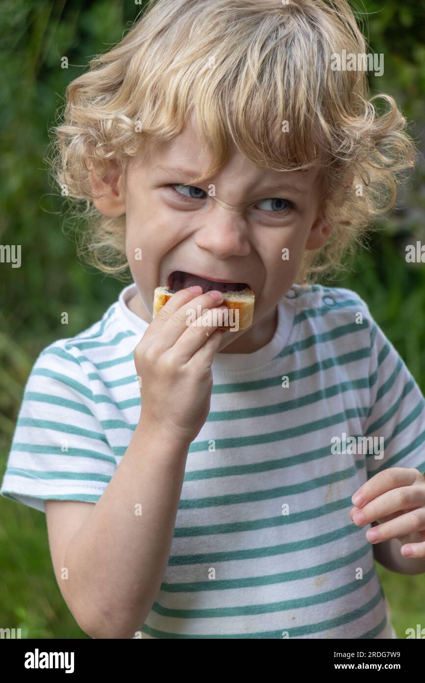 A little boy bites into a pastry Stock Photo - Alamy