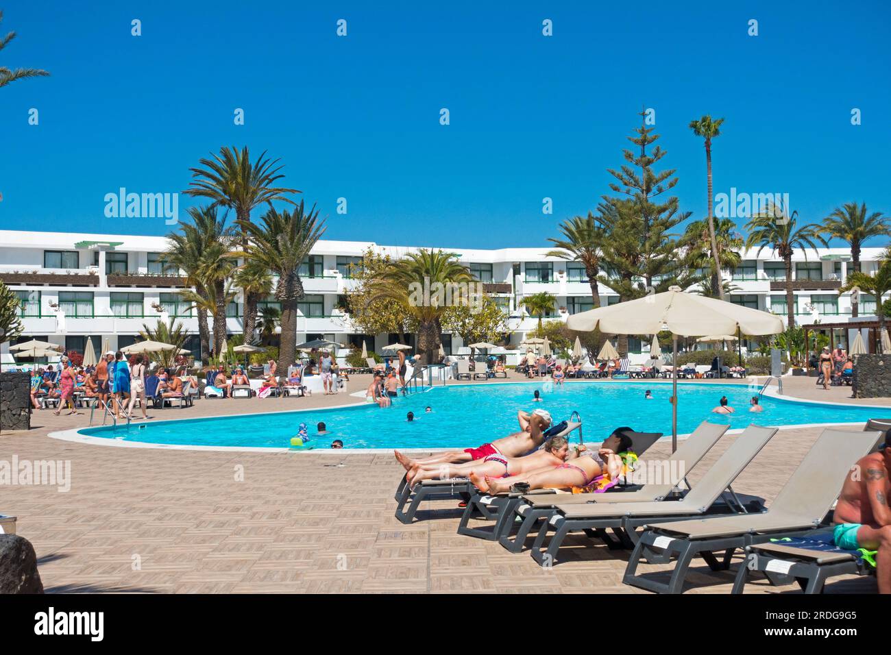 Typical view of guests sunning themselves around a swimming pool in a ...