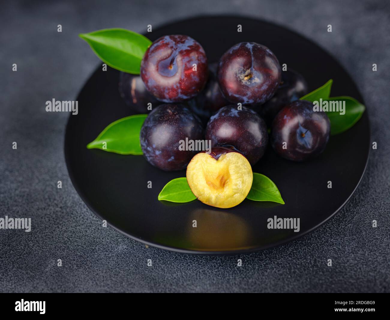 Sweet plums on dark background. Fresh blue plums with leaves. Food ...
