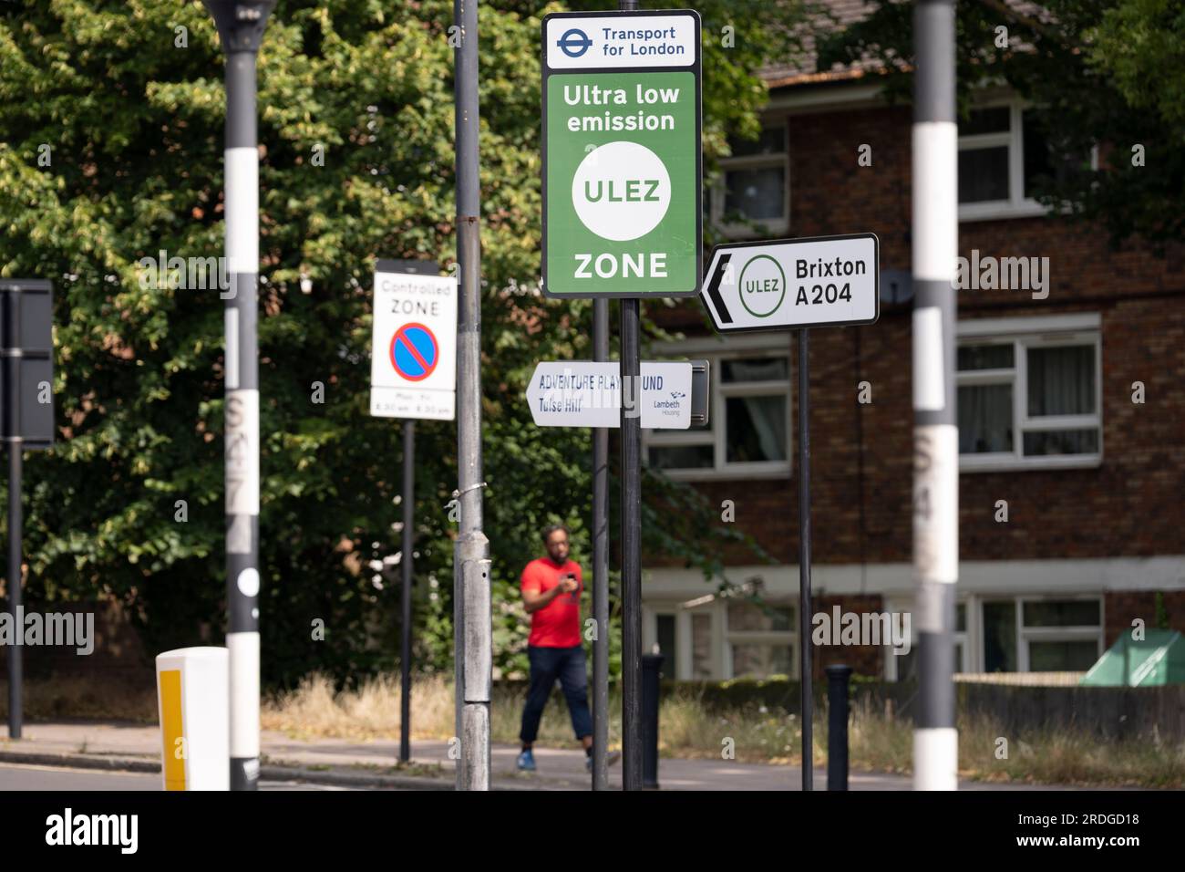 A pedestrian passes beneath an ULEZ (Ultra Low Emission Zone) sign on ...