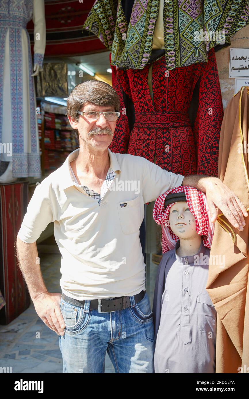 Shopkeeper standing outside his shop with an arm resting on a ...