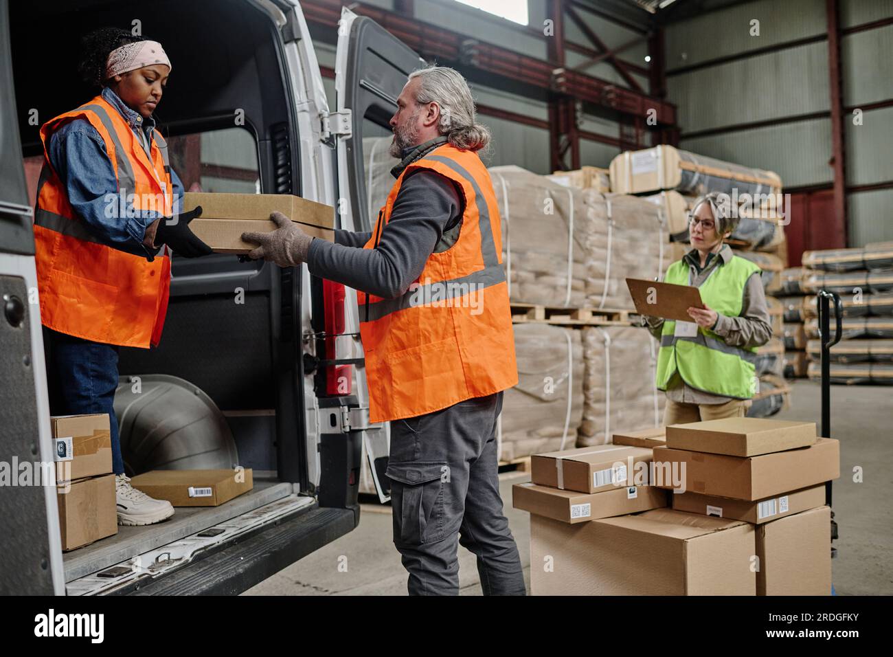 Warehouse workers loading cargo in truck with foreman controlling the ...