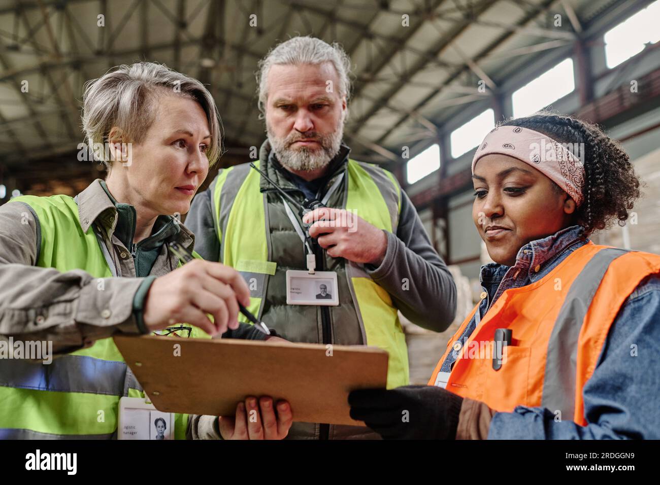 Foreman pointing at document and discussing invoice with workers during ...