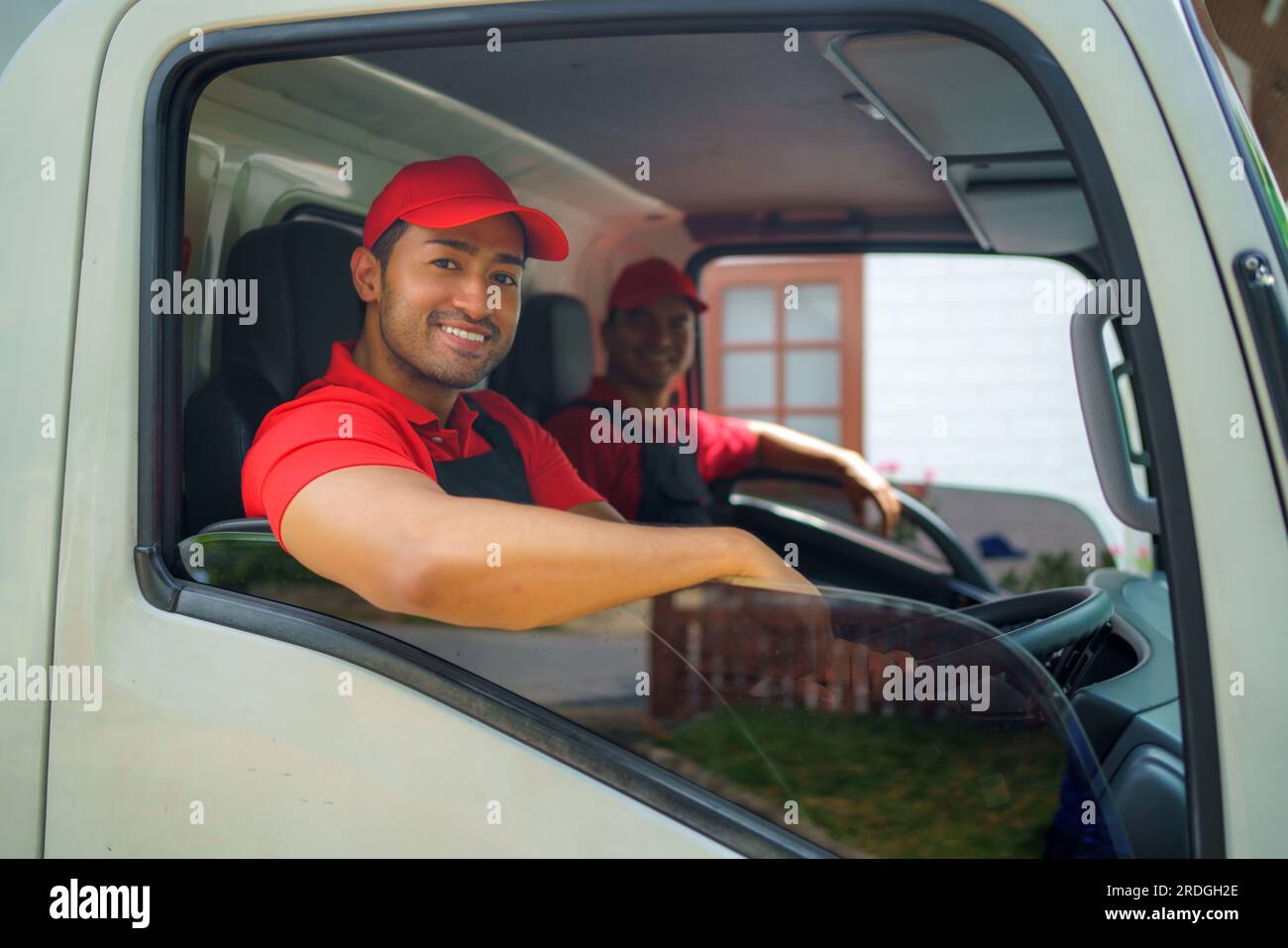 Transport worker sits in the cargo truck, smiling with readiness and ...