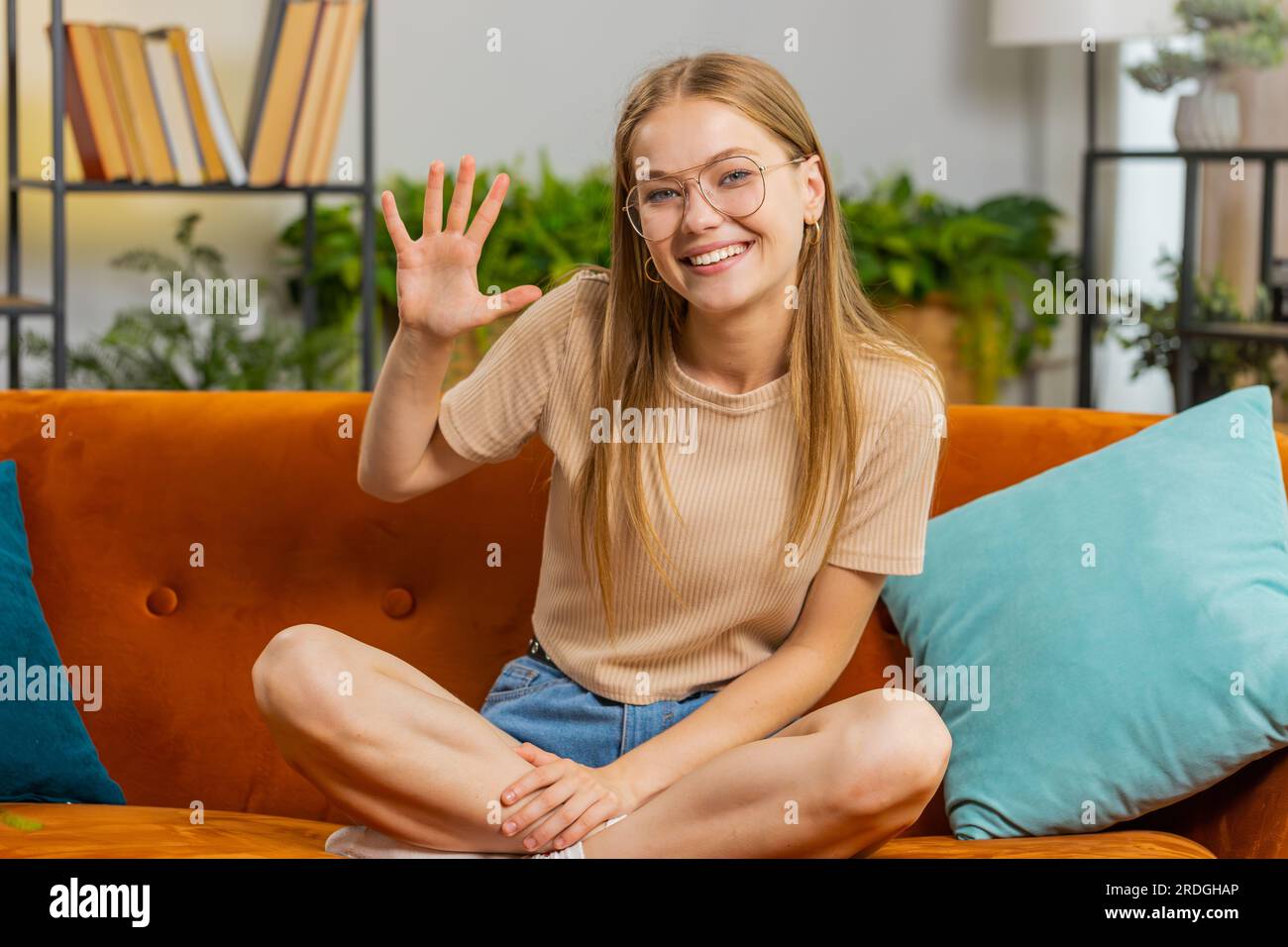 Hello. Young woman smiling friendly at camera and waving hands ...