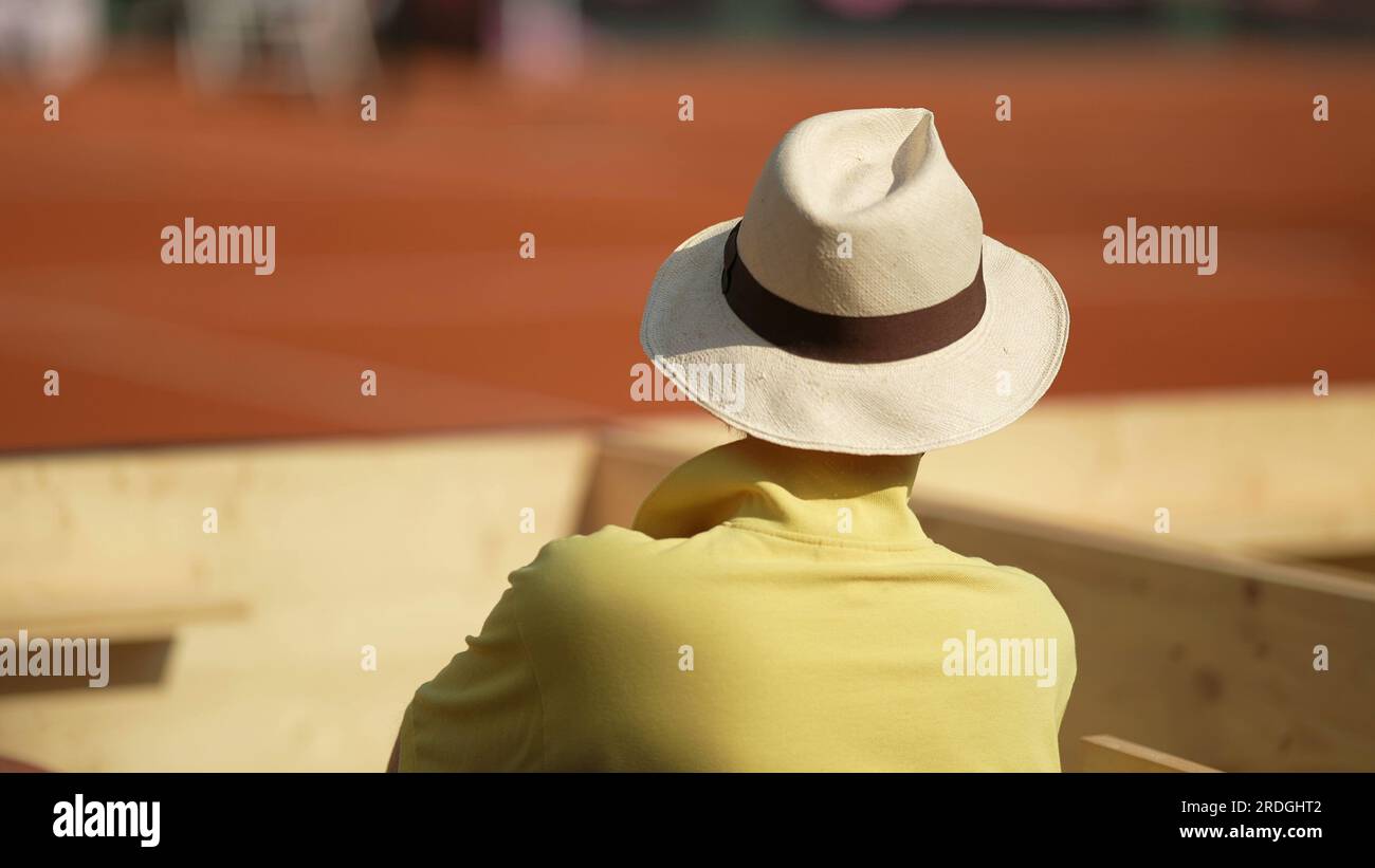 Spectator watching sport match game from stadium seat wearing panama ...