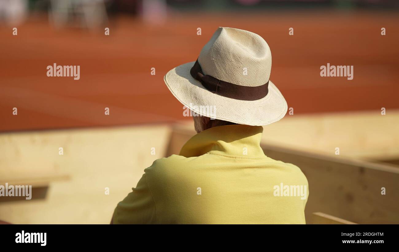Spectator watching sport match game from stadium seat wearing panama ...