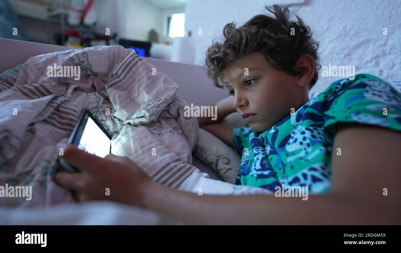 One addicted child staring at cellphone screen in the morning bed Stock ...