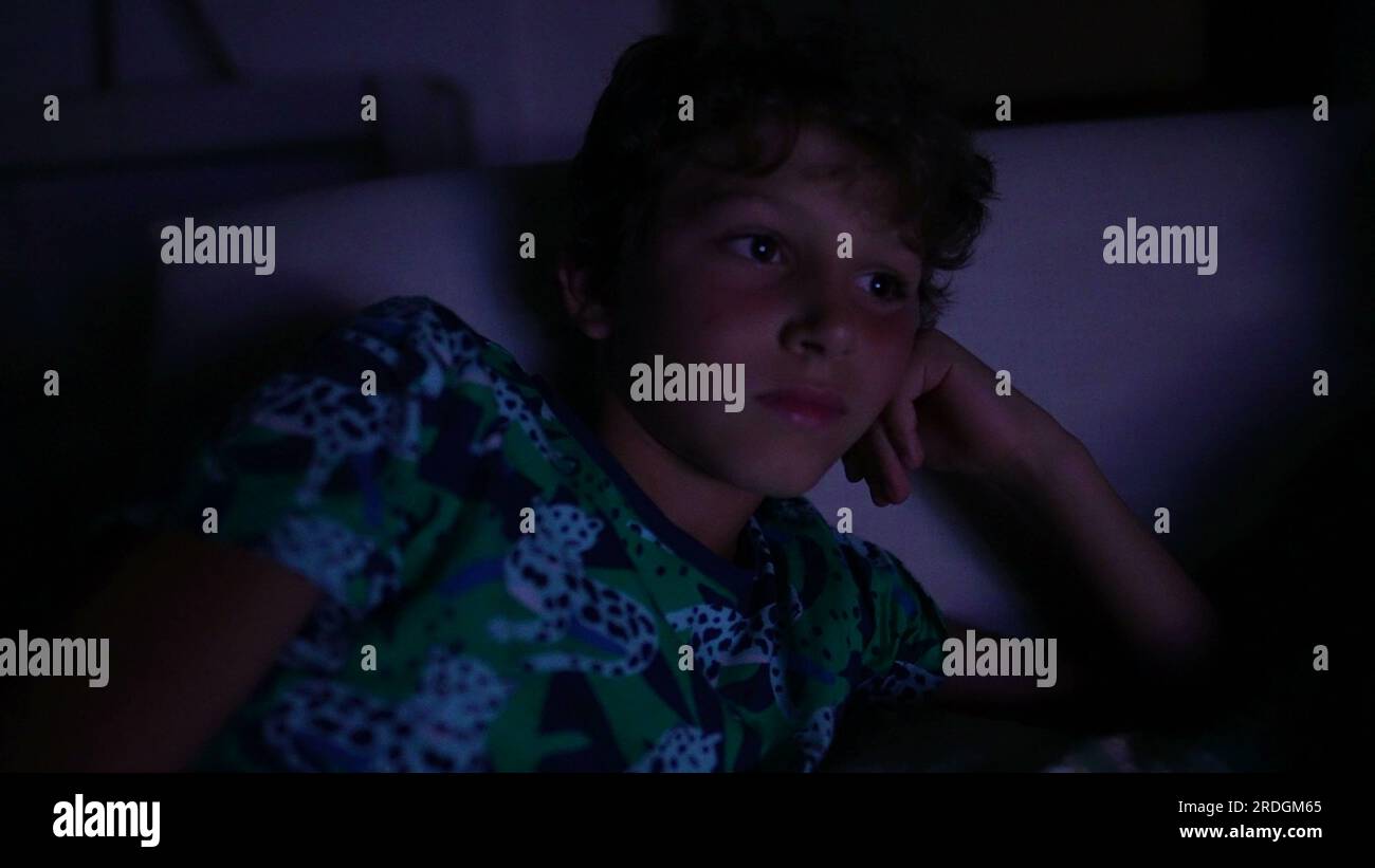 Young boy staring at movie entertainment at night Stock Photo - Alamy