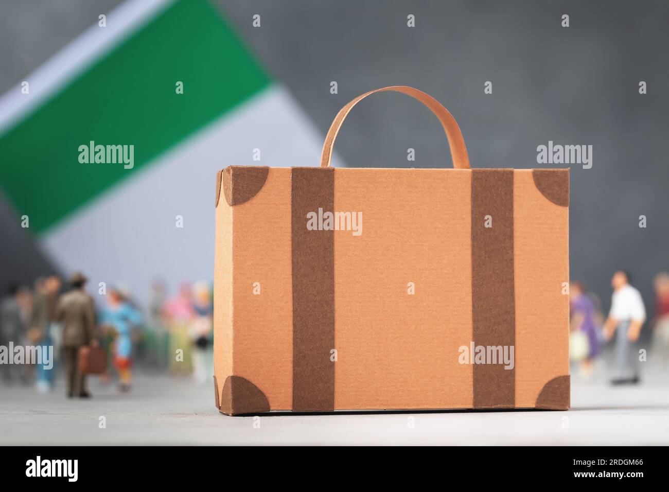Cardboard suitcase, plastic toy people and a flag on an abstract ...
