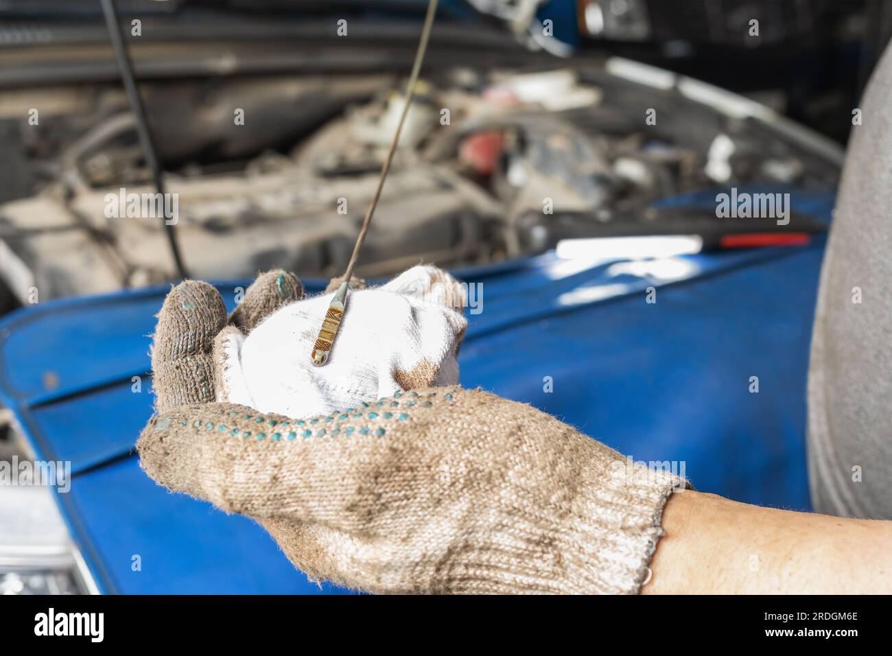 A man is engaged in car maintenance, checks the engine oil level after ...