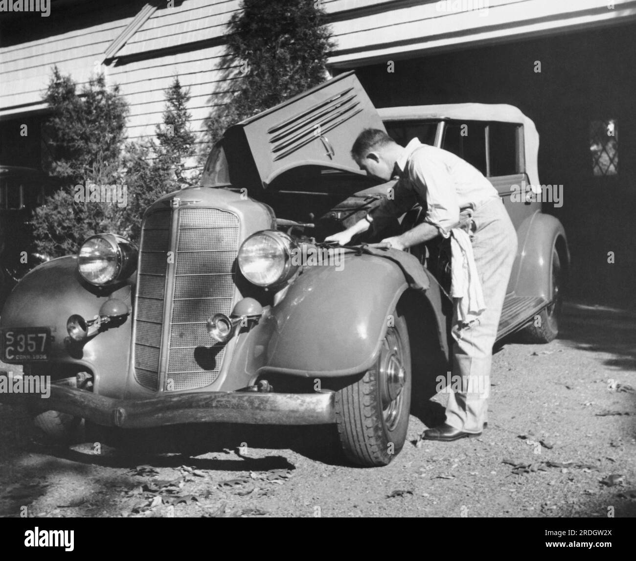 Connecticutt: 1936 A man working on his car in front of his garage ...
