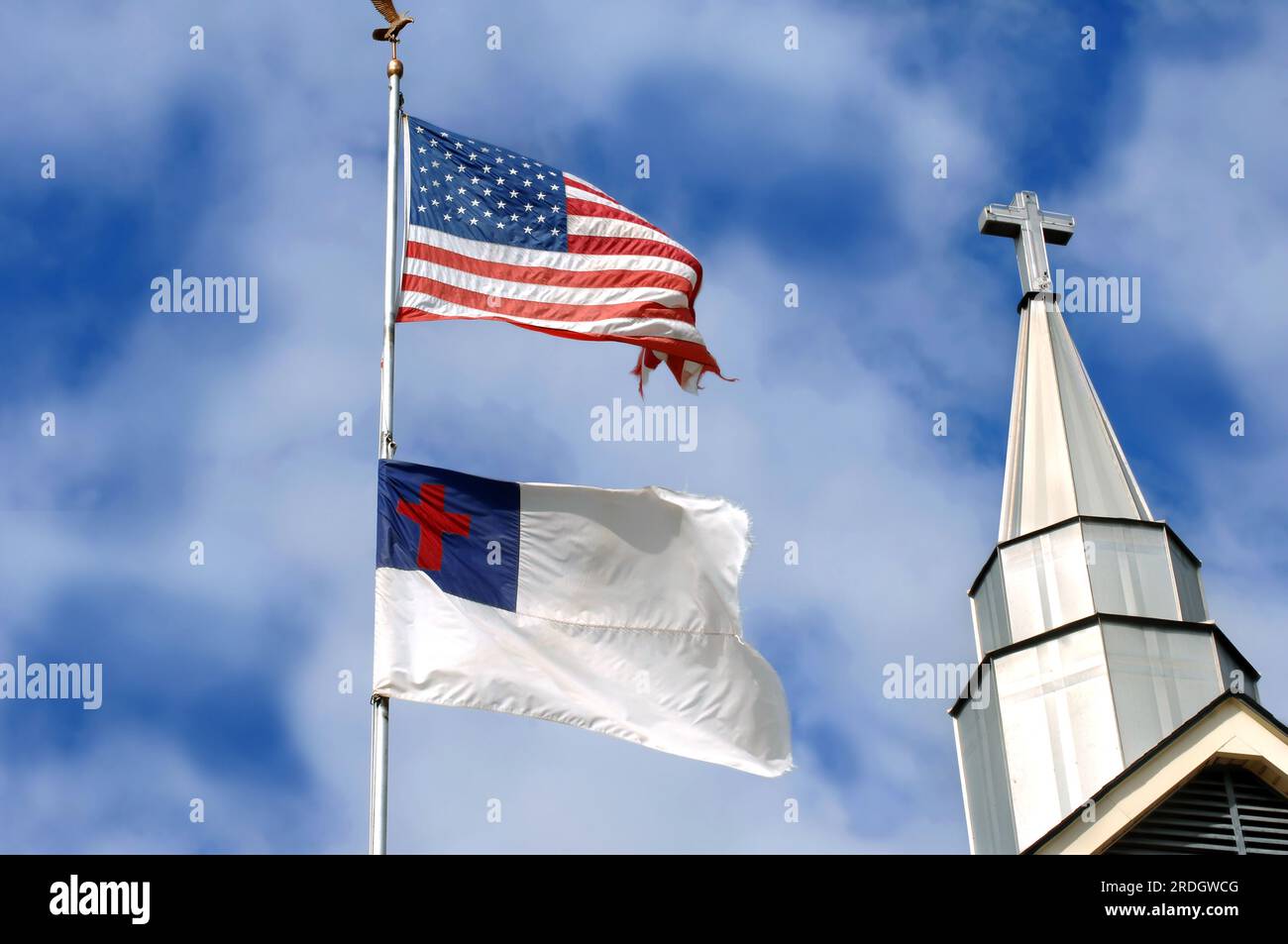 American flag and Christian flag fly besides a church steeple. Cross ...