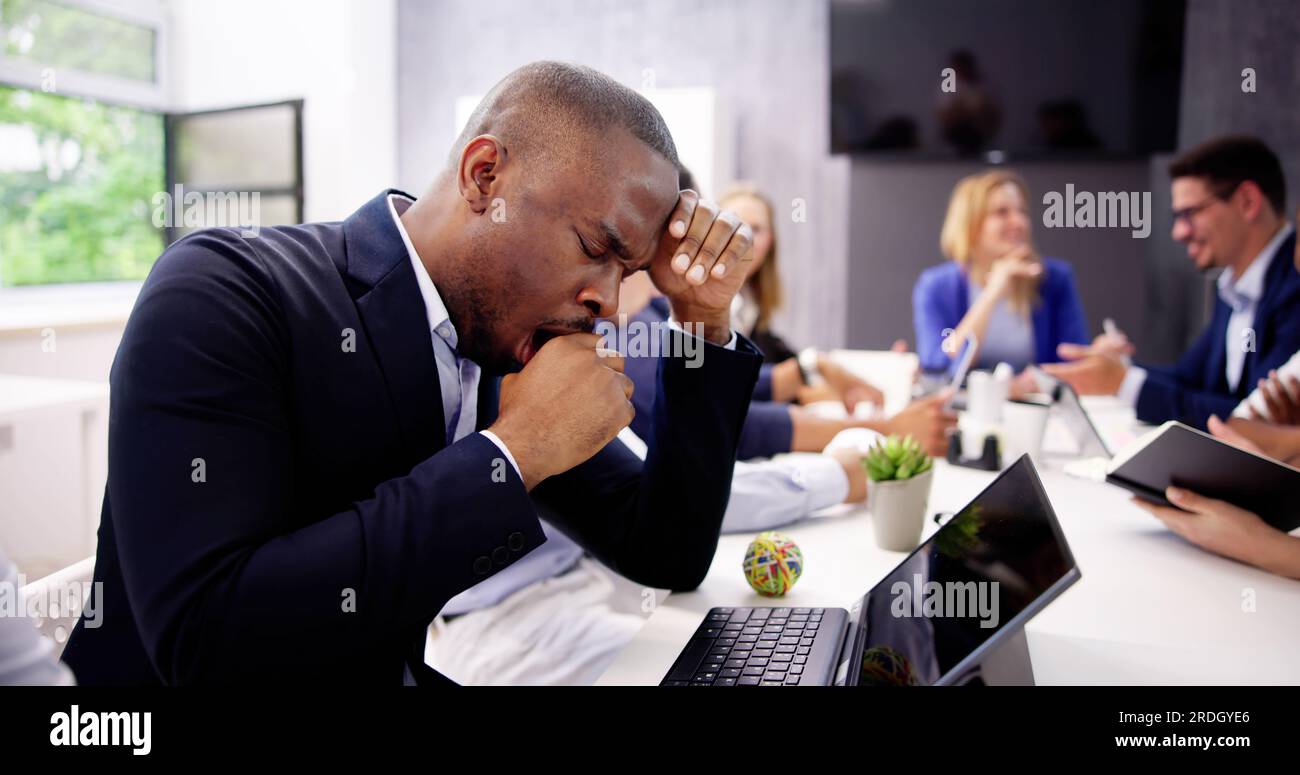 Tired Young Businessman Yawning At His Workplace Stock Photo - Alamy