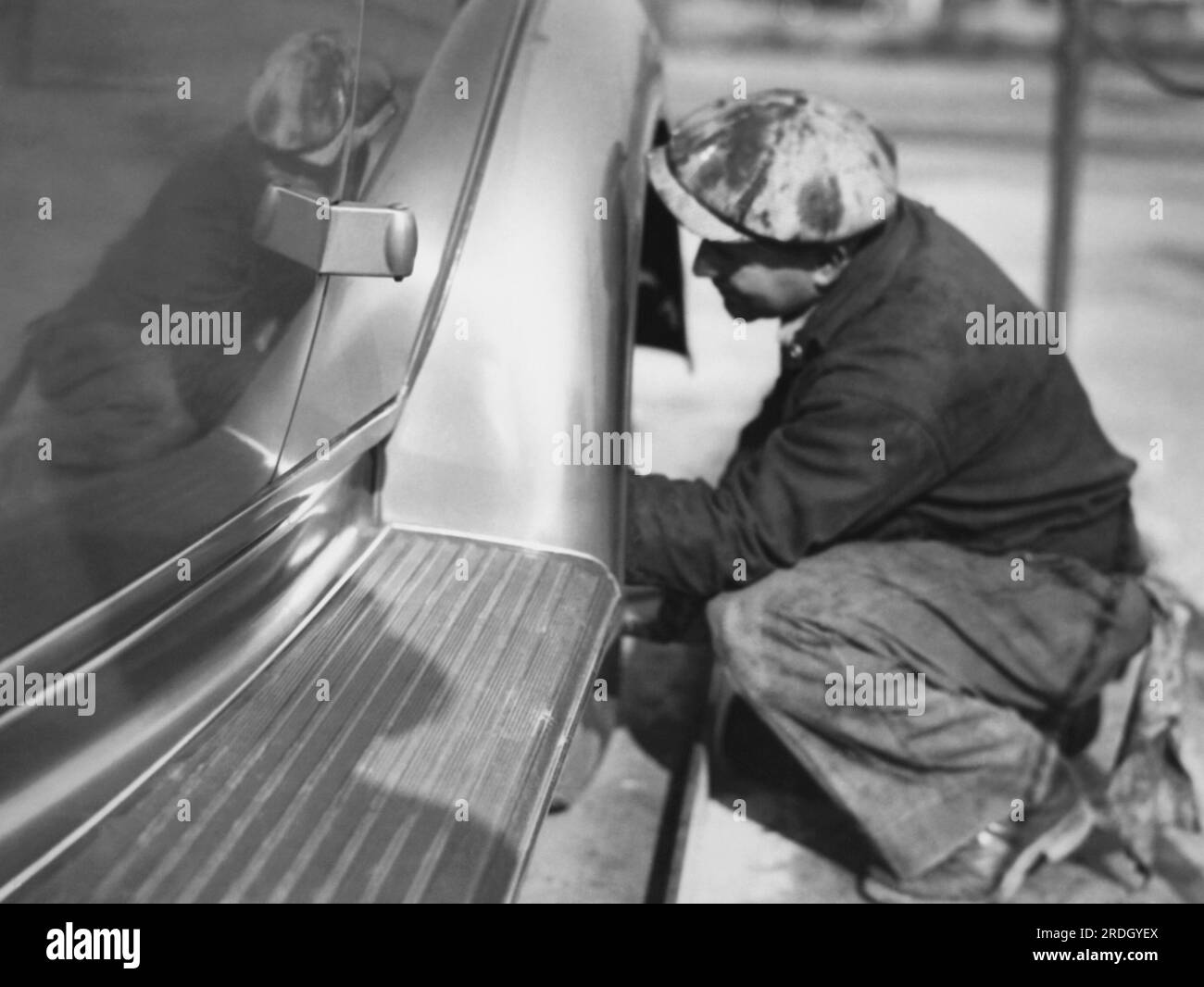 United States: c. 1925 A mechanic working on the wheel of a car Stock ...