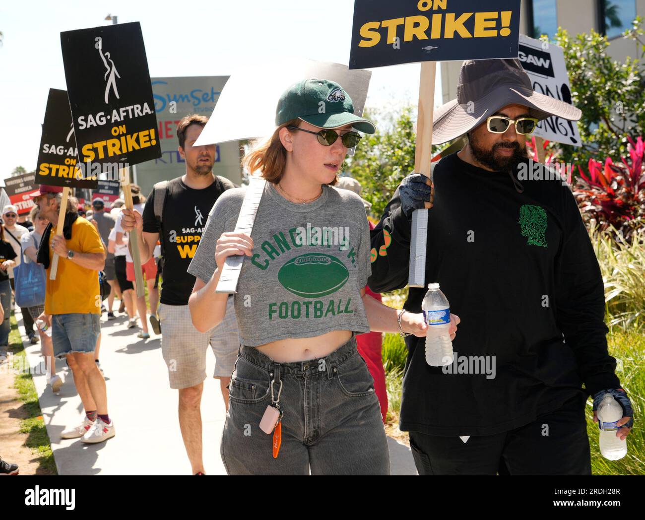 Hannah Einbender, second right, and Marc Maron, left, walk on a picket ...