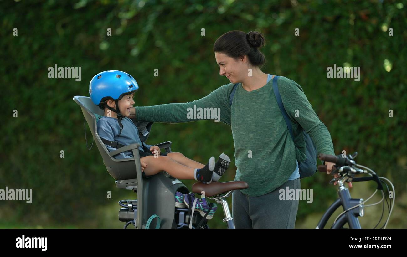 Mother and child together child sitting bicycle seat laughing with mom ...