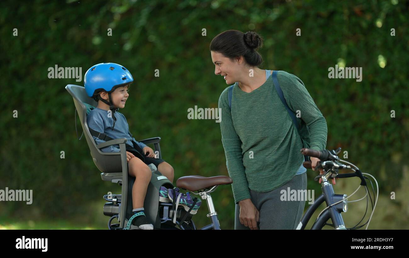 Mother and child together child sitting bicycle seat laughing with mom ...