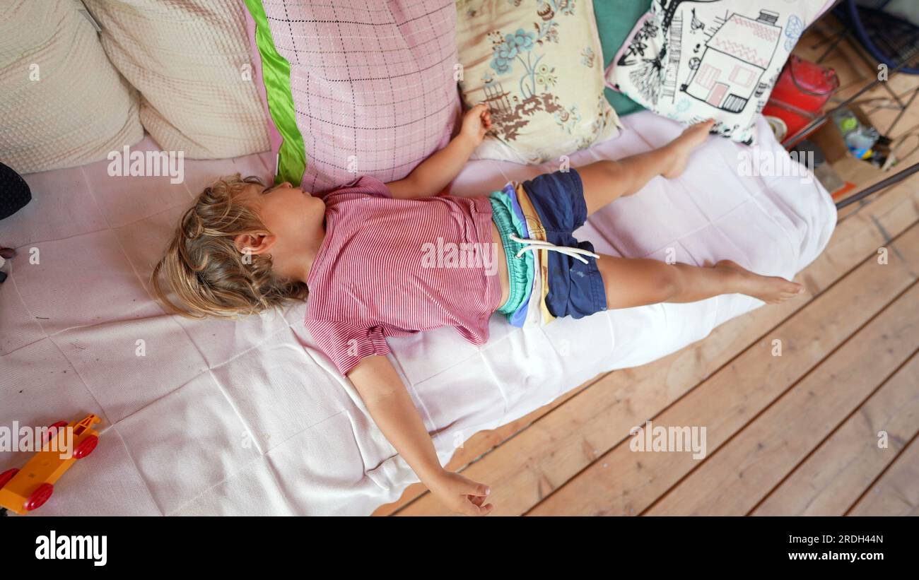 Small boy lying down on sofa sleeping during afternoon nap resting ...